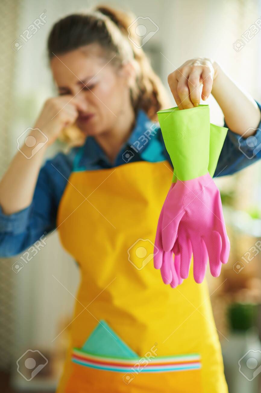 Disgusted 40 Years Old Housewife In Orange Apron And Pink Rubber Gloves In The Modern House In Sunny Day Holding Smelly Gloves. Stock Photo Picture and Royalty Free Image. Image 148455592