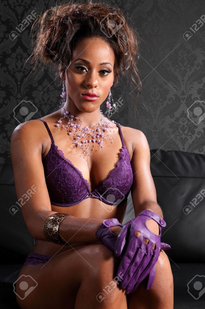 Stunning Young African American Glamour Model Woman Wearing Sexy Purple Lace Lingerie And Leather Gloves Sitting On Black Leather Sofa. Model Has Fashion Necklace And Bracelet On. Stock Photo Picture ...