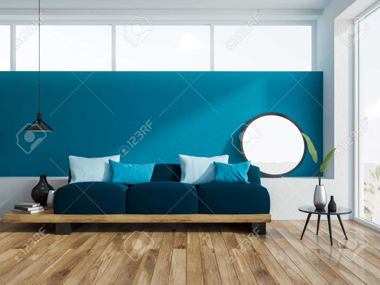 Blue Living Room Interior With A Wooden Floor A Loft Window And A Long Comfortable Dark Blue Sofa With Navy Cushions On It. A Round Mirror. 3d Rendering Mock Up Stock Photo