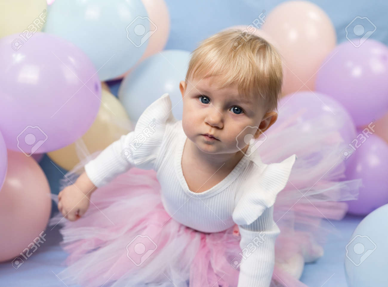 A Beautiful Little Girl 1 Year Old In A Pink Tutu Skirt Among Balloons Looks Up At The Camera Zdj cia royalty free obrazki obrazy oraz fotografia seryjna. Image 163920727